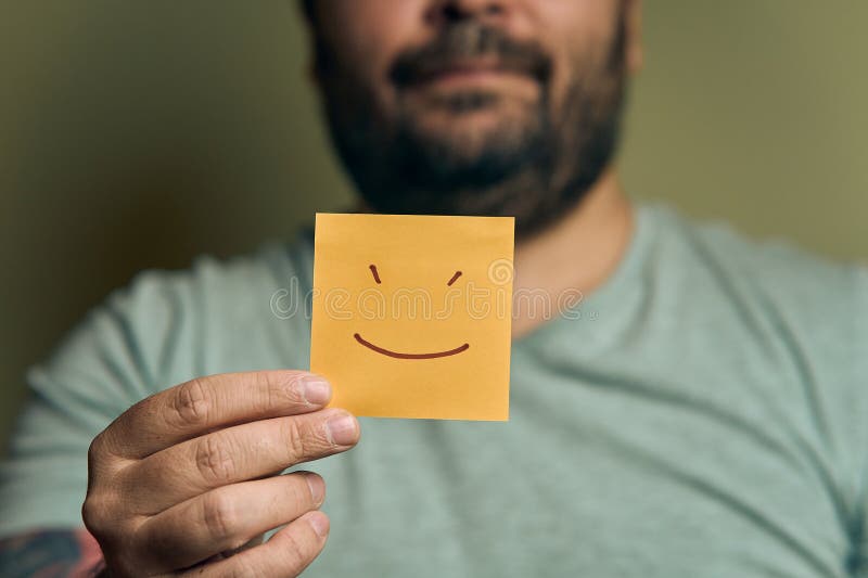 A Bearded European Man Holds a Orange Sticker in Front of Him, with a ...
