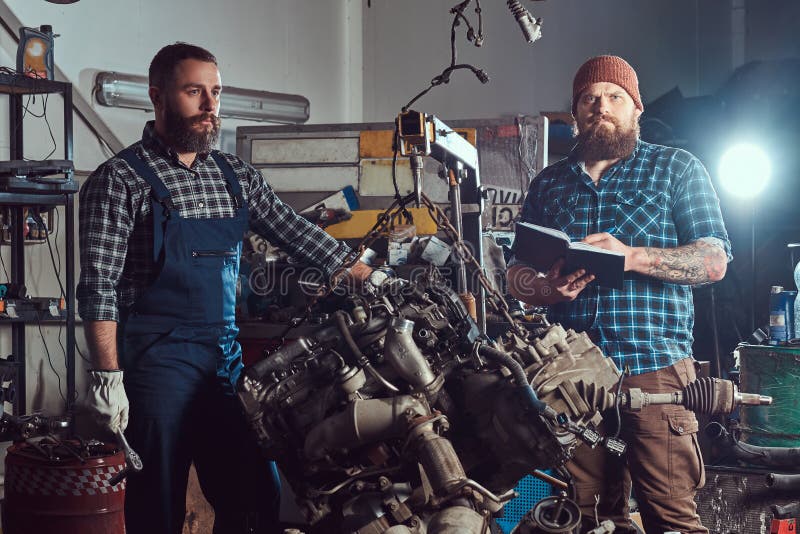 Two Bearded Mechanics Specialist Repairs the Car Engine Which is Raised ...
