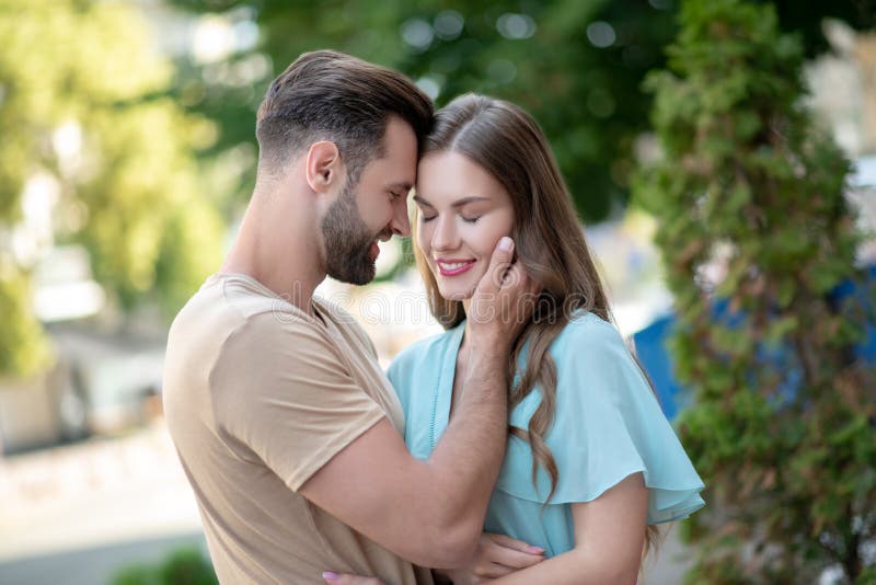 Bearded Male Hugging Female In Blue Dress Holding Her Chin Stock Image