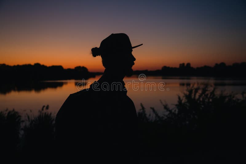 A Bearded Man with Backpack and with Cap at Sunset Near the Lake. Stock ...