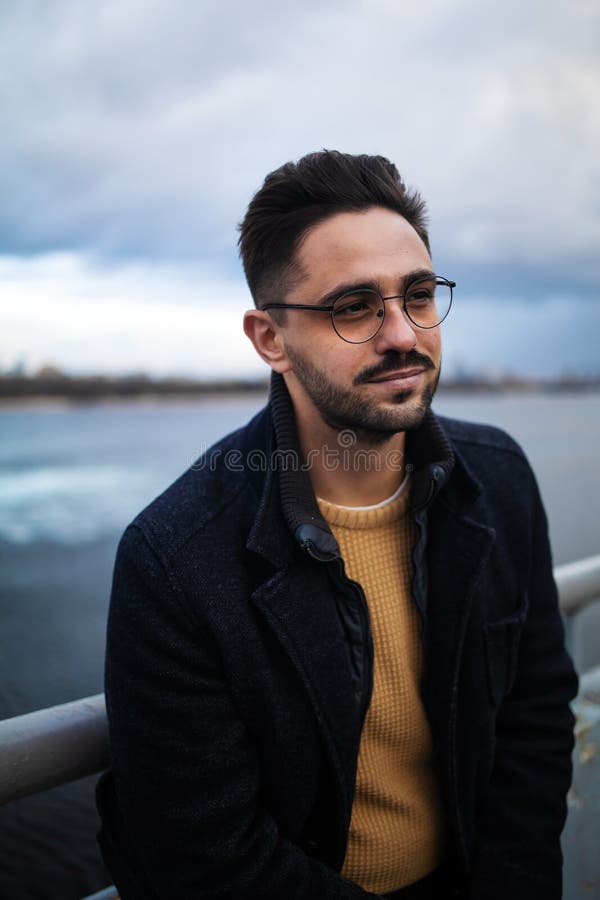 A Bearded Man with Glasses in a Winter Coat, Standing Leaning on the ...