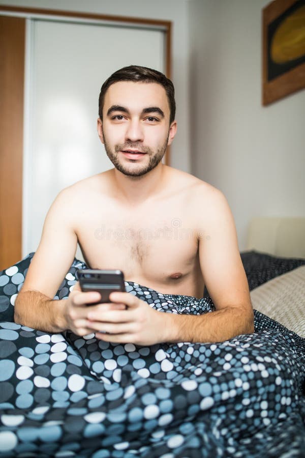 Bearded Man Lying In Morning Bed With Phone Using App Or Reading News