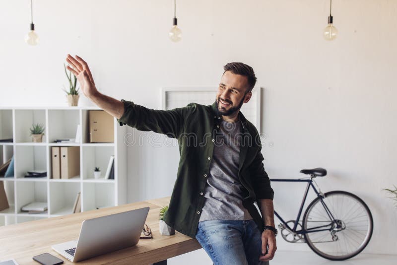 Bearded Man Sitting on Table with Laptop and Waving Hand Stock Image ...
