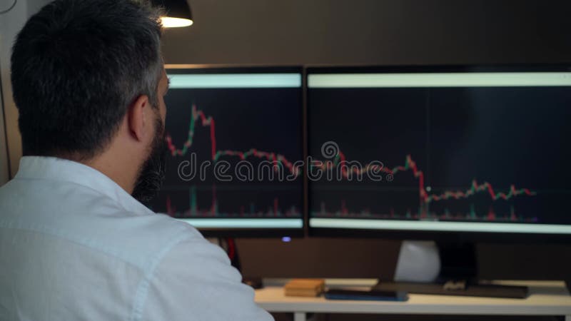 Bearded Man Trader Looks at Trading Charts on Desktop Computer Monitors ...