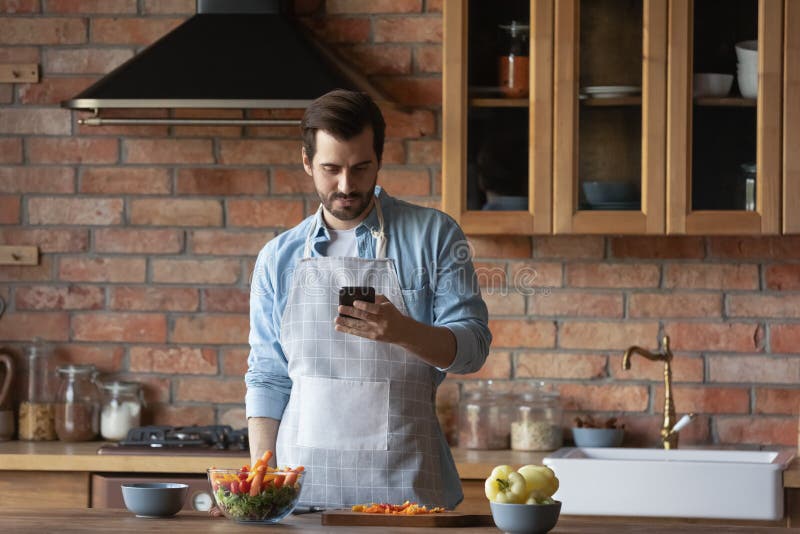 Bearded Man Using Smartphone, Distracted from Cooking in Kitchen Stock ...