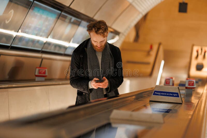 Bearded Man Using Smartphone while Standing on an Escalator in the ...