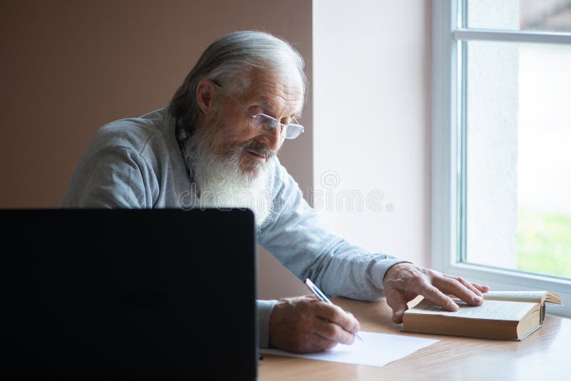 Senior Man with Laptop and Book Sitting at Table and Write Notes Stock ...