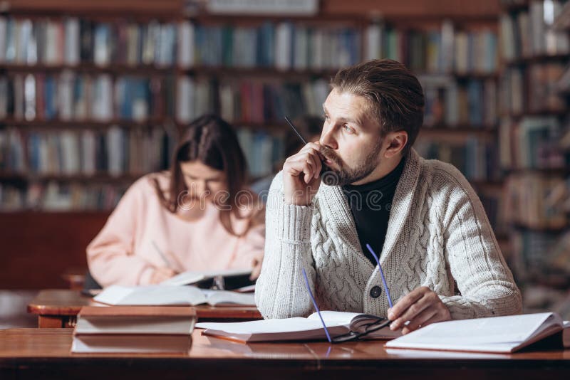 Bearded Reader In Casual Clothing Sitting At Library Stock Image