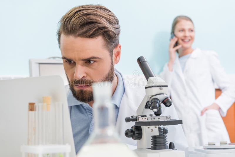 Bearded Scientist Working with Microscope and Laptop in Laboratory ...