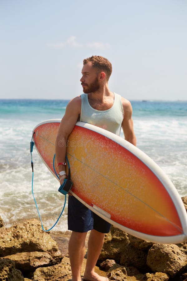 Bearded Surfer with a Surfboard is Walking on the Beach and Watching ...