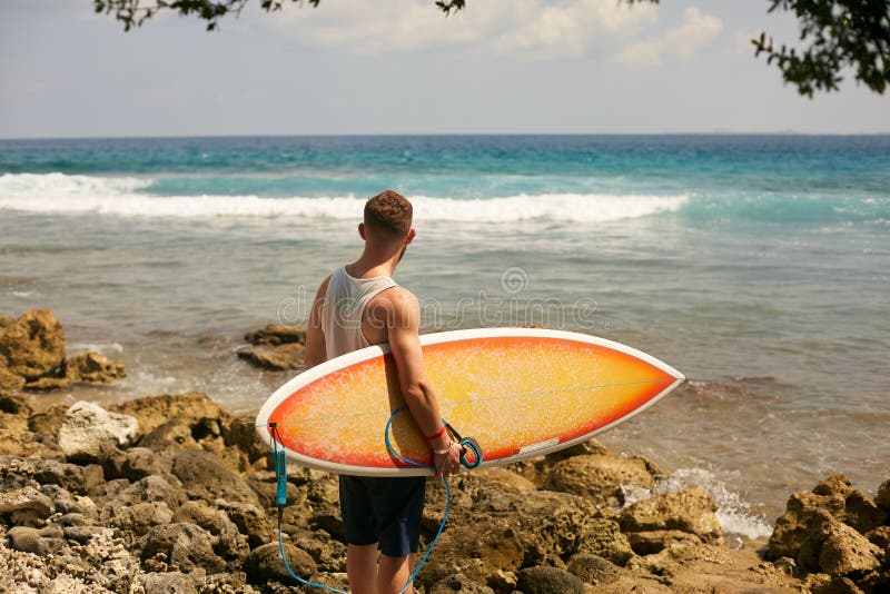 Bearded Surfer with a Surfboard is Walking on the Beach and Watching ...