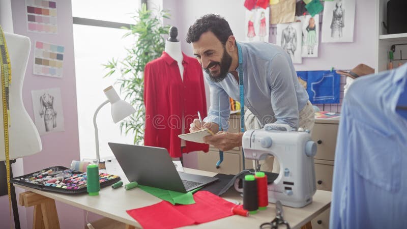 Bearded Tailor Taking Notes in Atelier with Sewing Machine, Mannequins ...