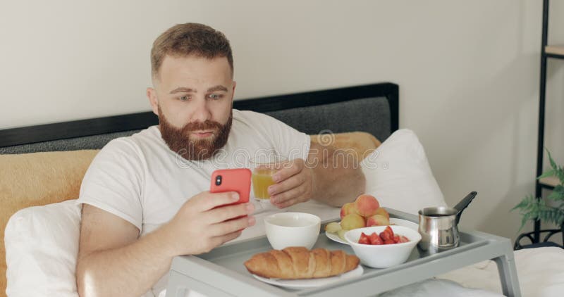 Bearded Young Man Choking on while Drinking Juice and Reading Shocking ...