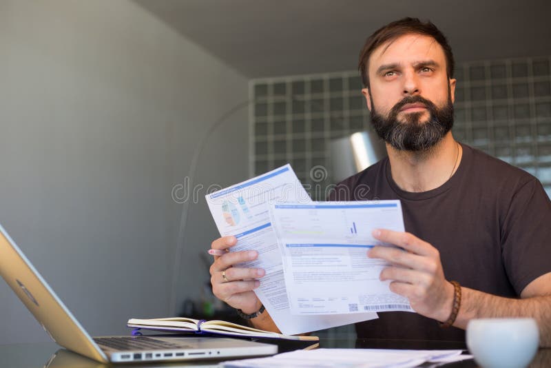 Bearded Young Man Sitting at Table Looking at Documents and Thinking ...