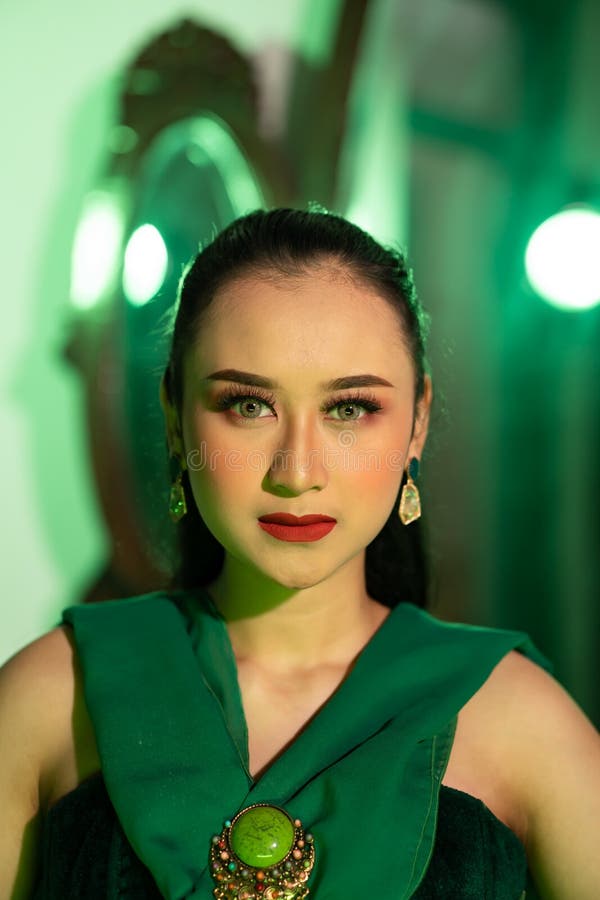 A Beautiful Asian Woman In A Green Dress Has A Very Exotic Face With