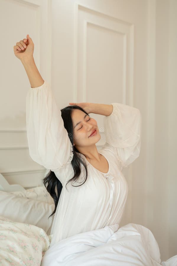 A Beautiful Asian Woman In Long Dress Pajamas Is Stretching Her Arms