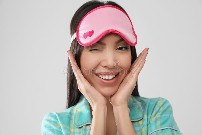 Beautiful Asian Woman Wearing Pajamas And Sleeping Mask On Grey