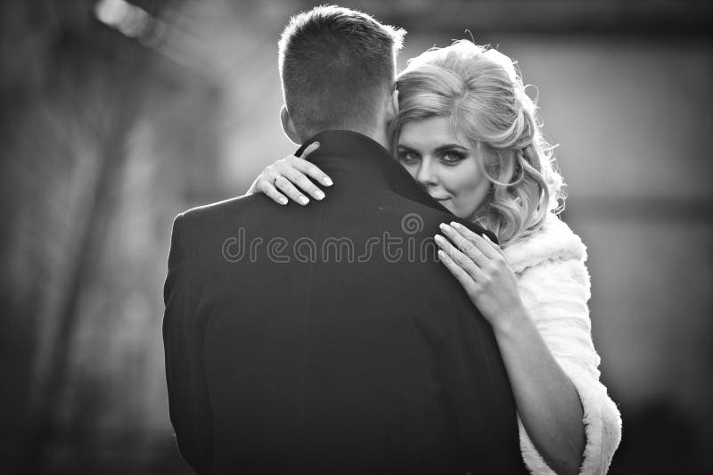 Beautiful Blonde Bride Hugging Handsome Groom In Black Coat In T Stock