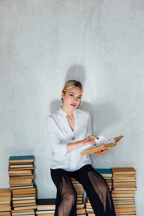 Beautiful Blonde Woman Sitting on Stacks of Books in Library Stock ...