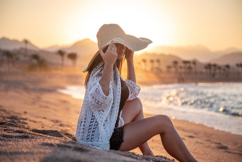 Beautiful Boho Model in a Hat Poses on the Beach in the Sun Stock Photo ...