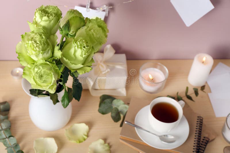 Beautiful Bouquet of Green Roses, Cup of Tea and Candles on Table Stock ...