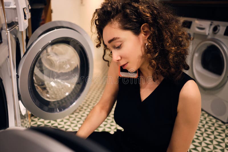 Beautiful Brunette Girl Talking On Smartphone Washing Clothes In Self