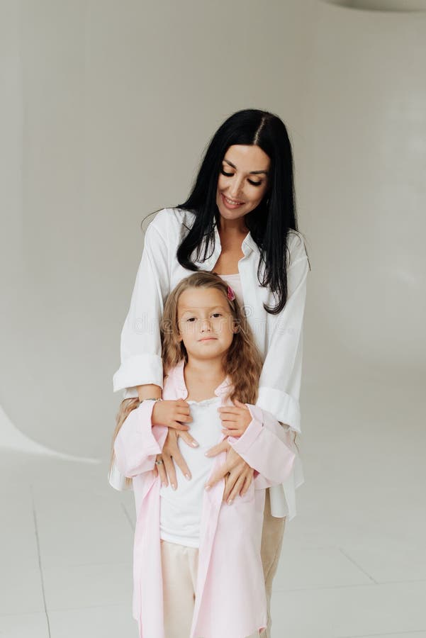 Beautiful Brunette Mom With Her Daughter On A Wall Background Stock
