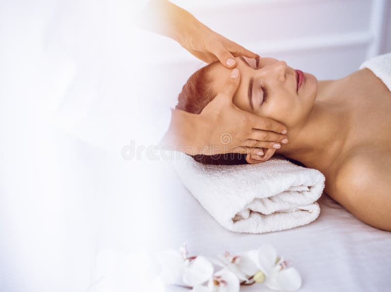 Beautiful Brunette Woman Enjoying Facial Massage With Closed Eyes In