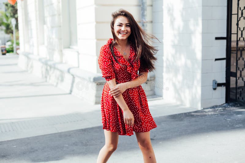 Beautiful Brunette Woman In Red Dress In Polka Dots Walks In The Street