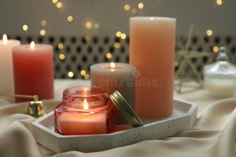 Beautiful Burning Candles on Fabric Against Blurred Lights Stock Image ...