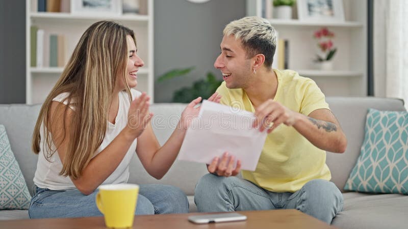 Beautiful Couple Reading Document Sitting on Sofa Celebrating at Home ...