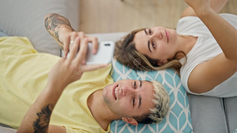 Beautiful Couple Using Smartphones Lying on Sofa at Home Stock Image ...