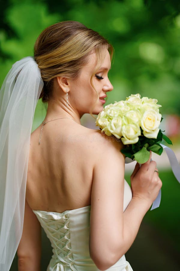 Beautiful and Delicate Bride in Veil and with a Bouquet of White Roses ...