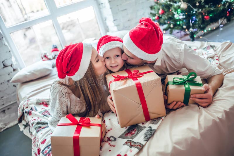 Happy Parents Kissing Daughter and Giving Xmas Present Stock Image ... Happy Parents Kissing Daughter and Giving Xmas Present Stock Image ...