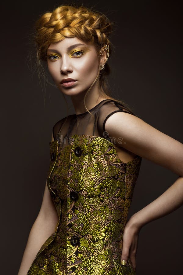 Beautiful Girl In A Gold Dress With Creative Makeup And Braids On Her