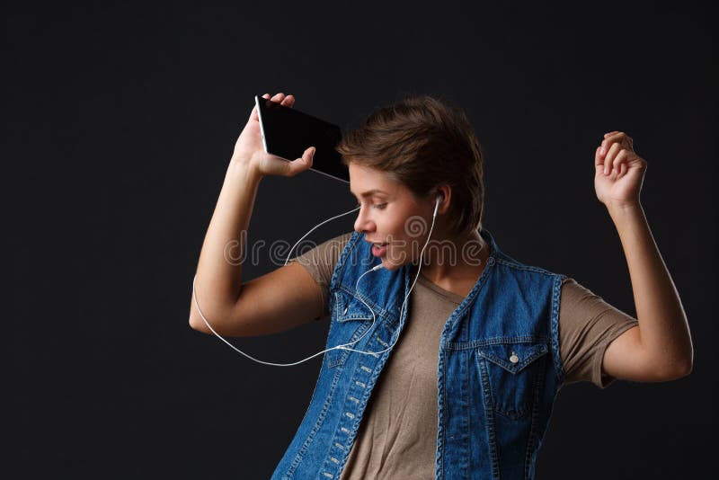 Beautiful Girl Listens To Music With Her Phone On A Black Background