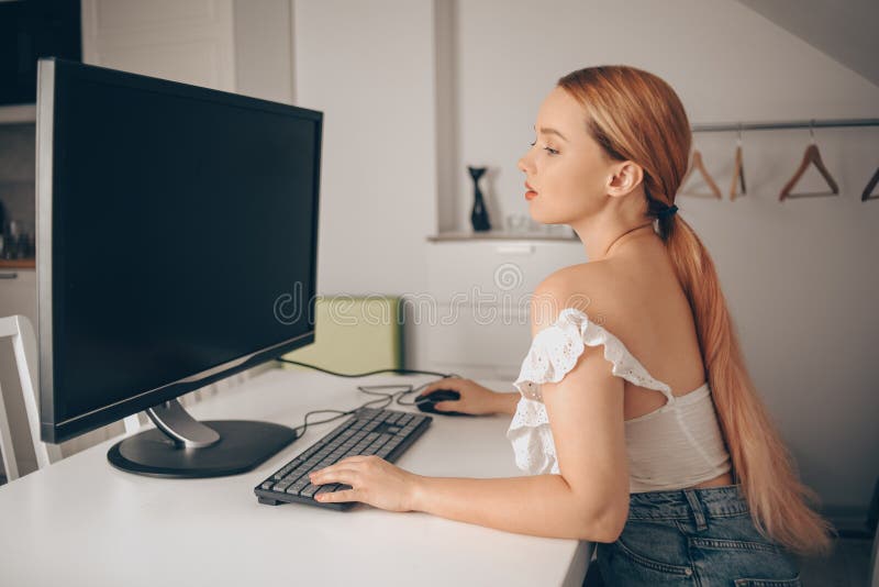 A Beautiful Girl Looks Into A Large Monitor And Prints Something Woman