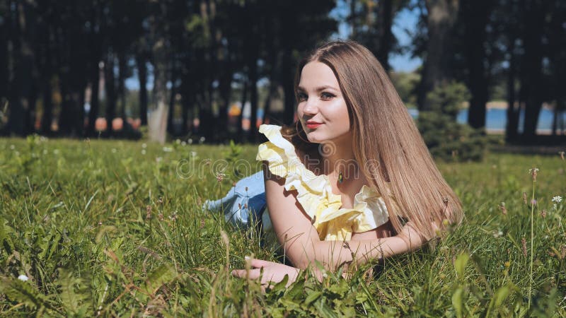 A Beautiful Girl Poses Lying on the Grass in the Park. Stock Photo ...