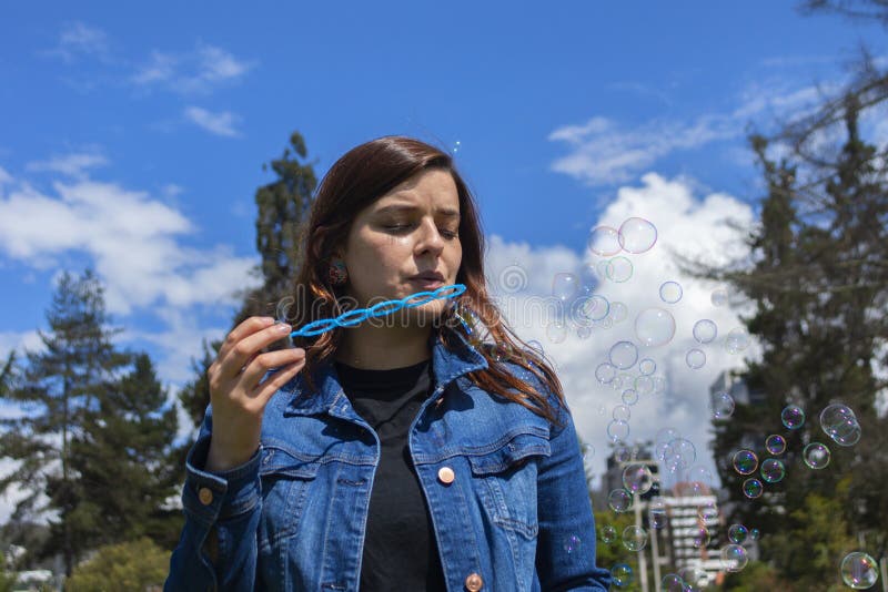 Beautiful Hispanic Woman Blowing Soap Bubbles In The Middle Of A Park