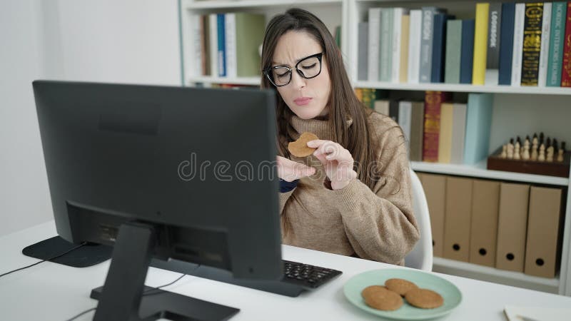 Beautiful Hispanic Woman Student Using Computer Eating Cookies at ...