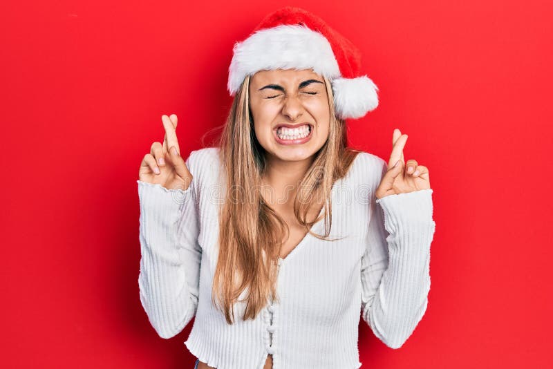 Beautiful Hispanic Woman Wearing Christmas Hat Gesturing Finger Crossed