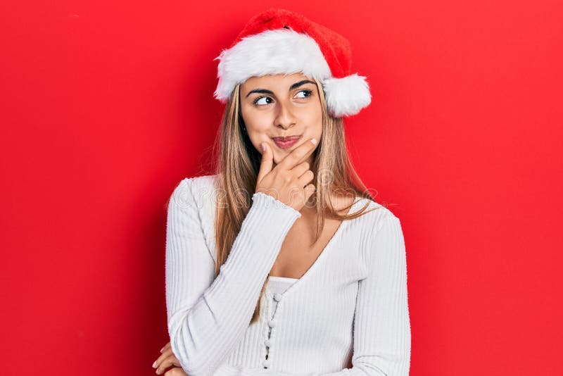 Beautiful Hispanic Woman Wearing Christmas Hat With Hand On Chin