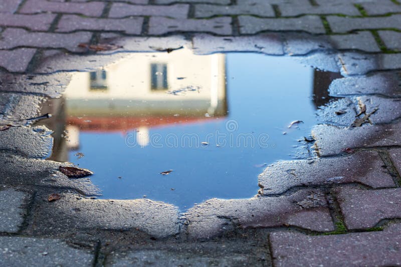 A Beautiful House is Reflected in a Small Puddle on a Brick Sidewalk ...