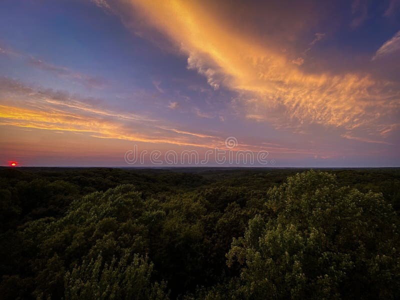 The Setting Sun is Set Over the Trees and Field Below Stock Image ...