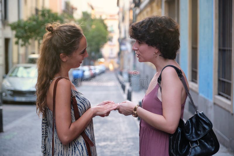 Beautiful Lesbian Couple Wearing Long Dresses Walking Holding Hands Along The Street Backwards