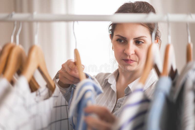 Young Beautiful Woman Stands Near The Closet And Hangs Up Her Clothes