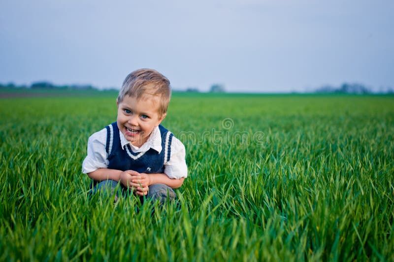 A Beautiful Little Boy Sitting in the Grass Stock Image - Image of ...