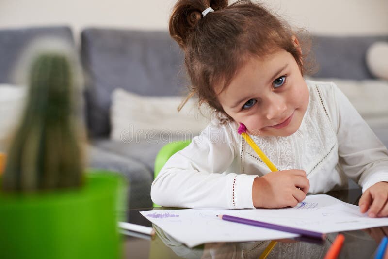 A Beautiful Little Girl Learning To Write and Looking at Camera Stock ...