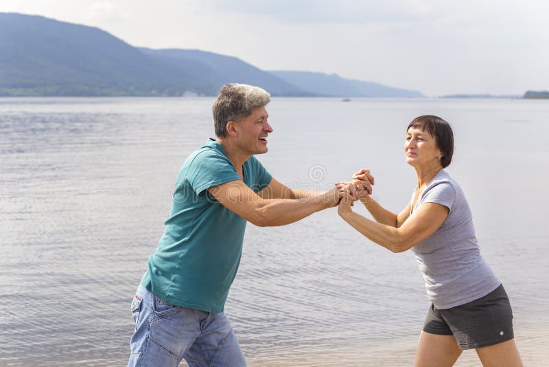 Beautiful Mature Sportive Couple Doing Gymnastic Exercises On The Beach