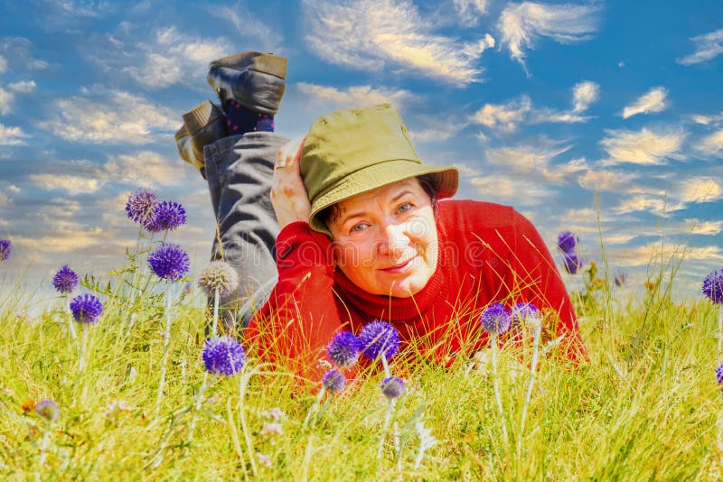 Beautiful Mature Woman Lies On The Grass Against The Blue Sky Stock